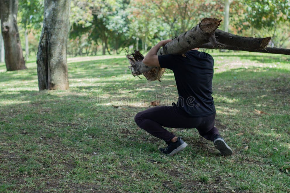 Young Man Lifting a Tree Trunk in a Forest. Lumberjack Cutting a Tree ...