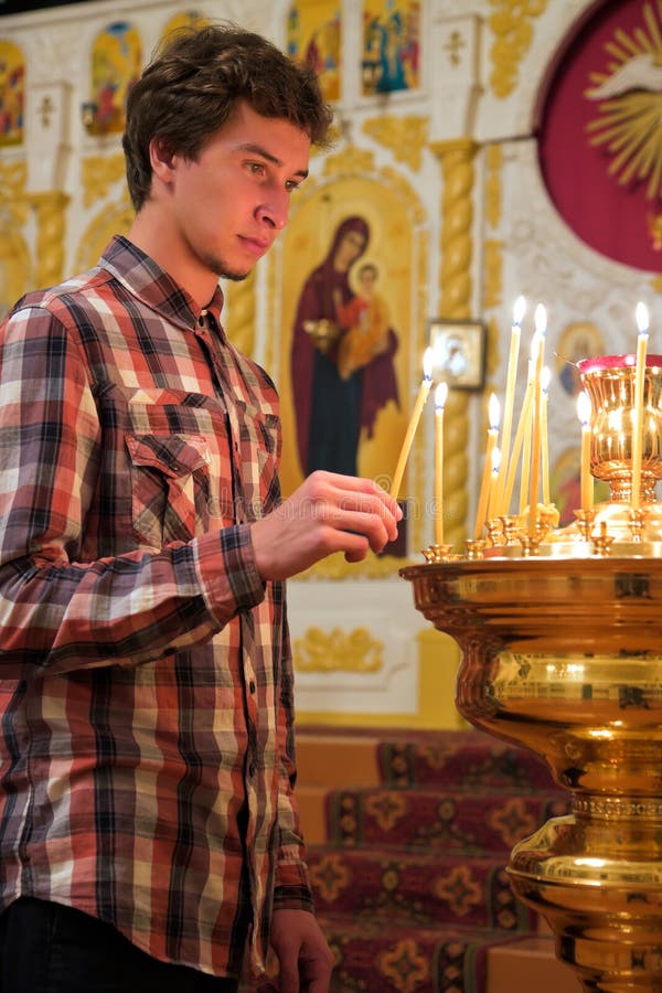 Young Man Lighting a Candle in the Church. Stock Image - Image of ...
