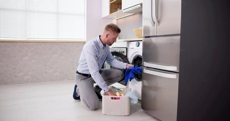 Young Man Loading Clothes into Washing Machine Stock Photo - Image of ...