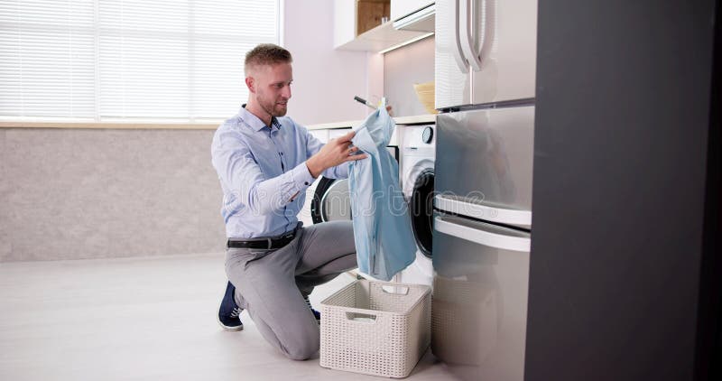 Young Man Loading Clothes into Washing Machine Stock Photo - Image of ...
