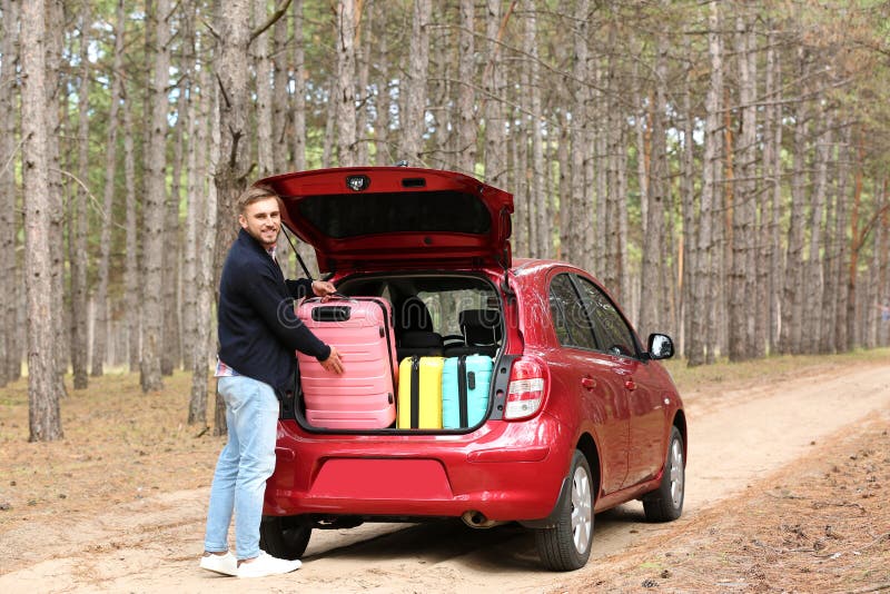 Young Man Loading Suitcase into Car Trunk Stock Image - Image of ...