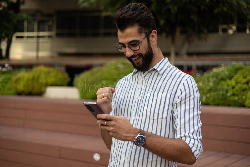 Young Man Looking at Cell Phone Excitedly Celebrating Stock Photo ...