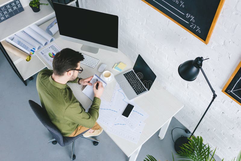 Young Man Looking at Computer Screen and Taking Notes Stock Photo ...