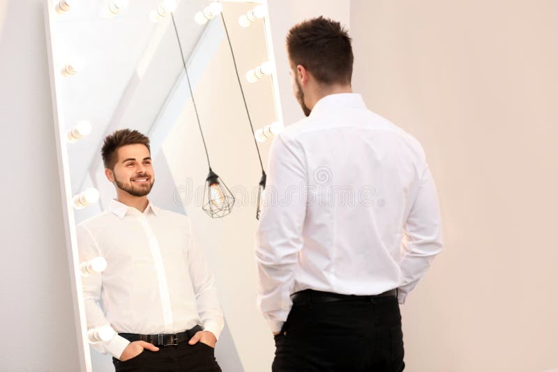 Young Man Looking at Himself in Large Mirror Stock Photo - Image of ...