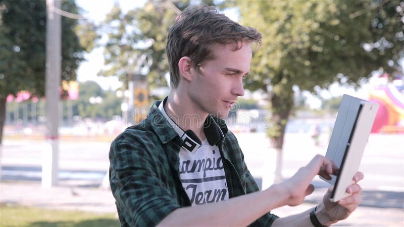 Young Man Looking at Map on His Tablet, Playing Pokemon GO in the City ...