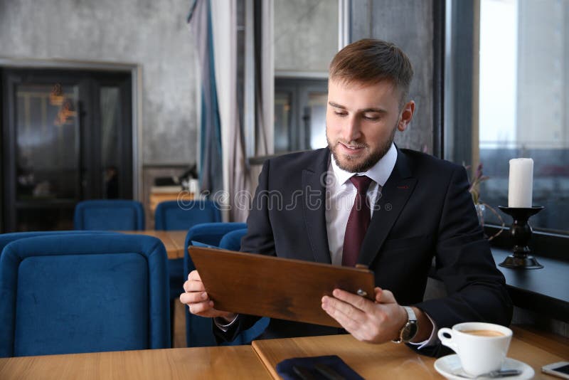 Young Man Looking through Menu in Restaurant Stock Image - Image of ...