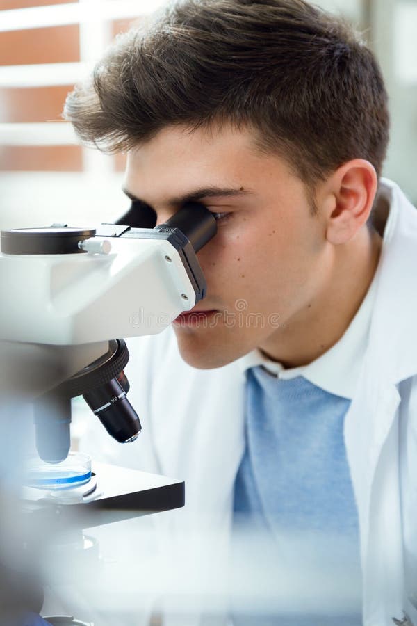 Young Man Looking through Microscope in Laboratory. Stock Image - Image ...