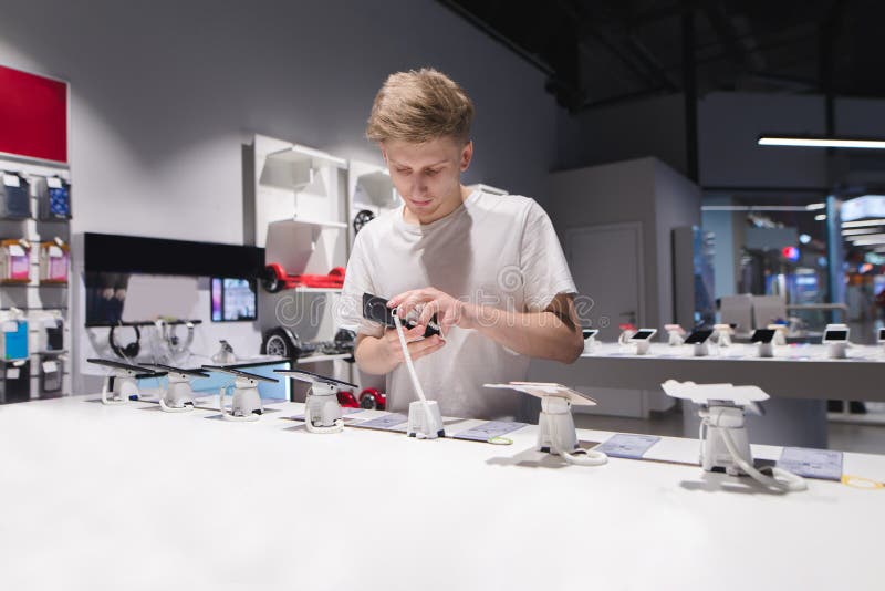 Young Man is Looking at a Smartphone in the Mobile Phone Department at ...