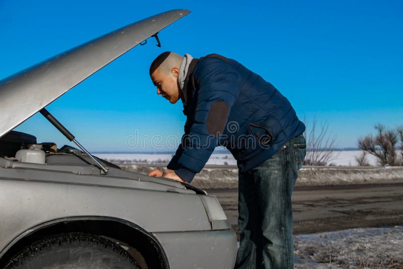 Young Man Looking Under Hood of Broken Car in Cold Winter Day Stock ...
