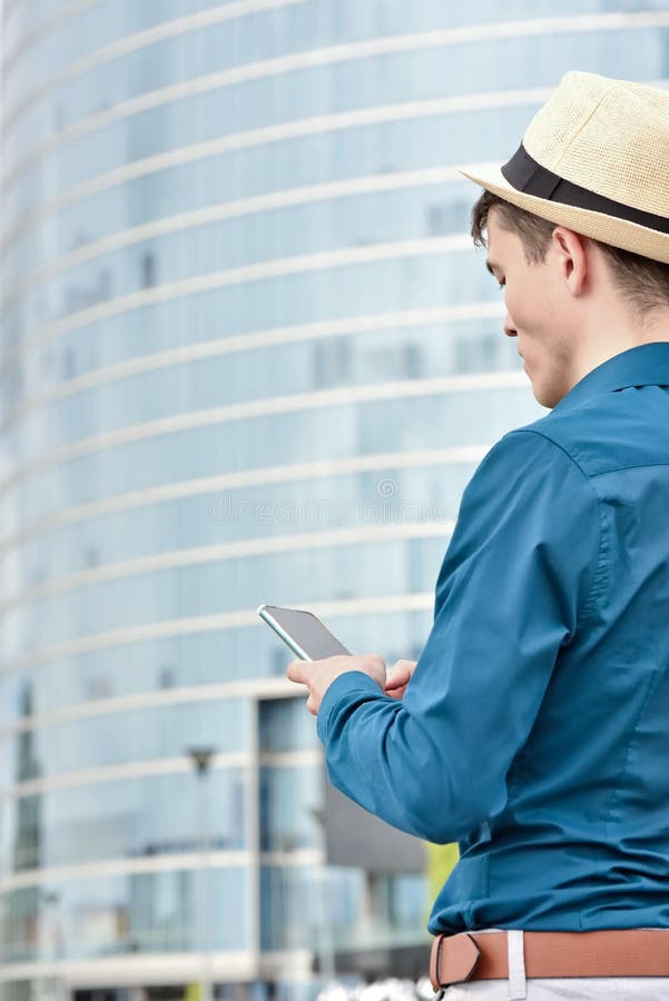 Young Man Looks at a Smartphone, Texting and Talking while Working and ...