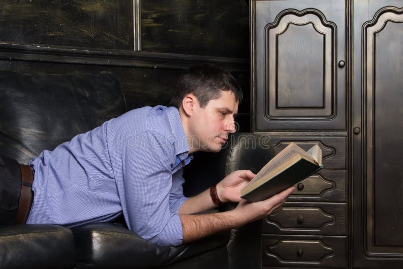 Young Man is Lying on the Sofa and is Reading a Book Stock Image ...