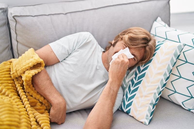Young Man Lying on Sofa Using Napkin at Home Stock Image - Image of ...