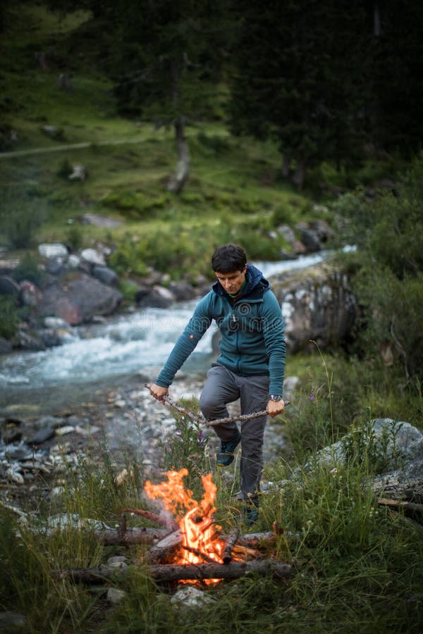 Young Man Making Fire while Camping Outdoors Stock Photo - Image of ...