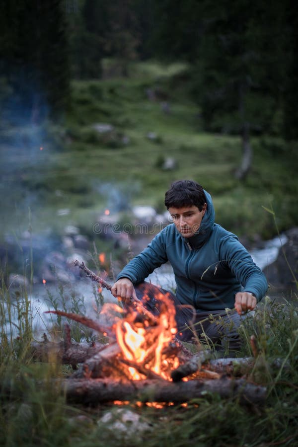 Young Man Making Fire while Camping Outdoors Stock Photo - Image of ...
