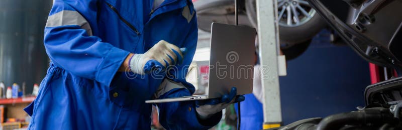 Young Man is Mechanic Using Laptop Computer Checking Engine of Car in ...