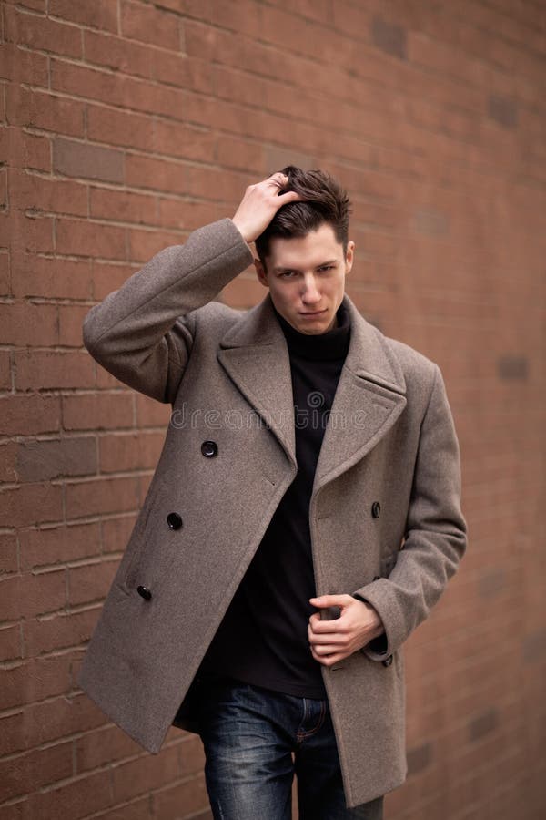 The Young Man Model in a Coat Poses at a Brick Wall. Toned Stock Image ...
