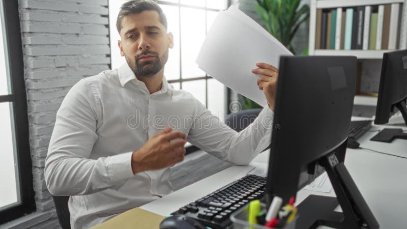 Young Man in Office Fanning with Documents Shows Bored Expression while ...