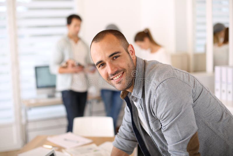 Young Man at Office Working, Colleagues in the Back Stock Photo - Image ...