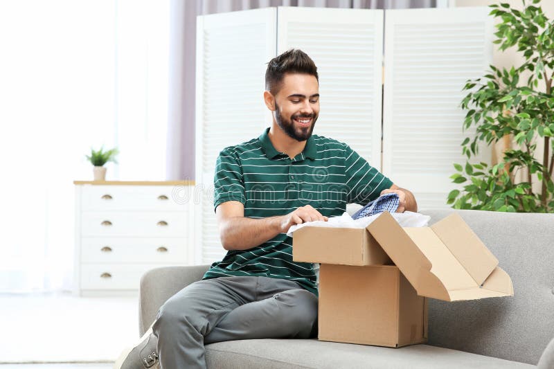 Young Man Opening Parcel on Sofa Stock Image - Image of receiving ...