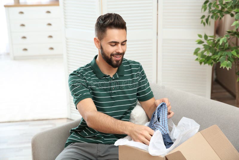 Young Man Opening Parcel on Sofa Stock Image - Image of happy ...