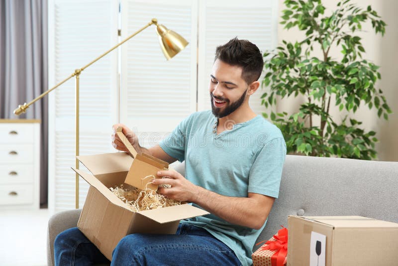 Young Man Opening Parcel on Sofa Stock Image - Image of person, mail ...