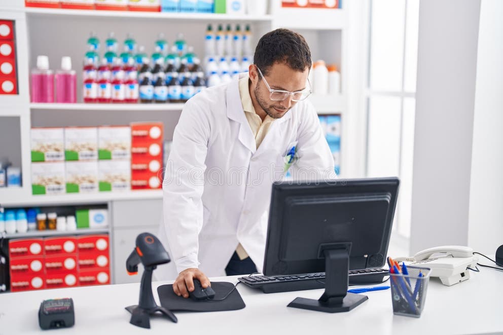 Young Man Pharmacist Using Computer Working at Pharmacy Stock Photo ...