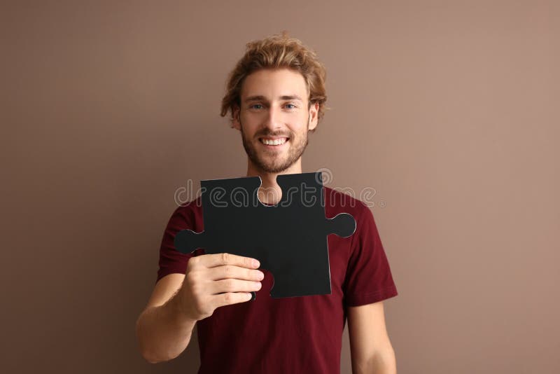 Young Man with Piece of Jigsaw Puzzle on Color Background Stock Photo ...