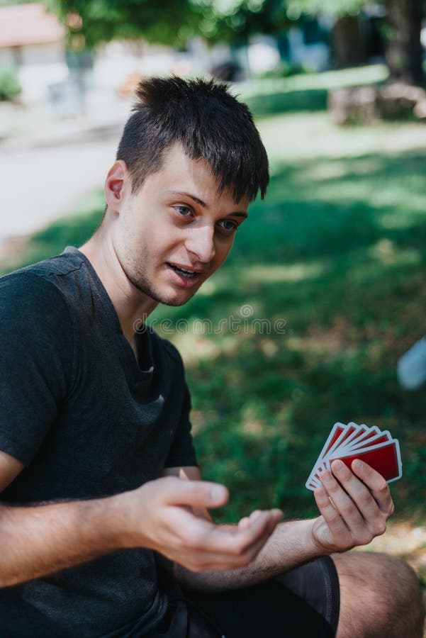 Young Man Playing Cards Outside in a Relaxed Setting Stock Photo ...