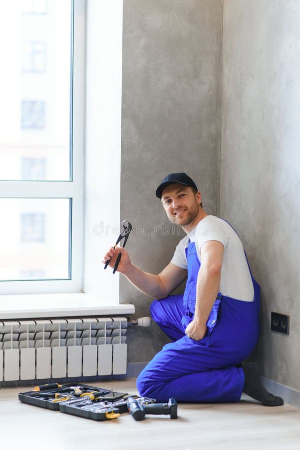 Young Man Plumber Checking Radiator while Installing Heating System in ...
