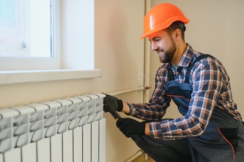 Young Man Plumber Checking Radiator while Installing Heating System in ...