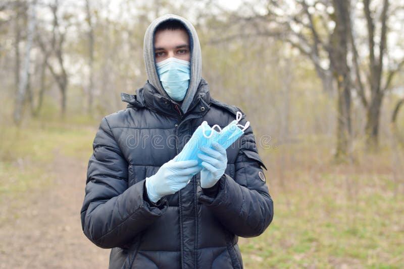 Young Man in Protective Mask Shows Bunch of Protective Face Masks ...