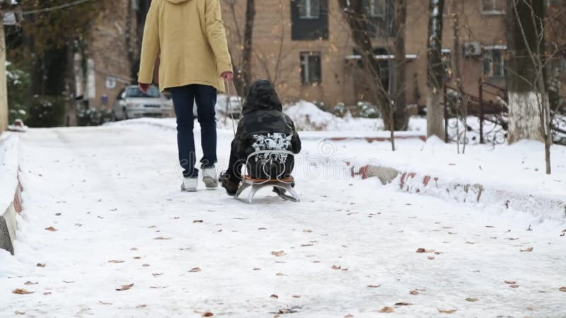 A Young Man Pulls a Sled through the Snow with His Young Son. There are ...