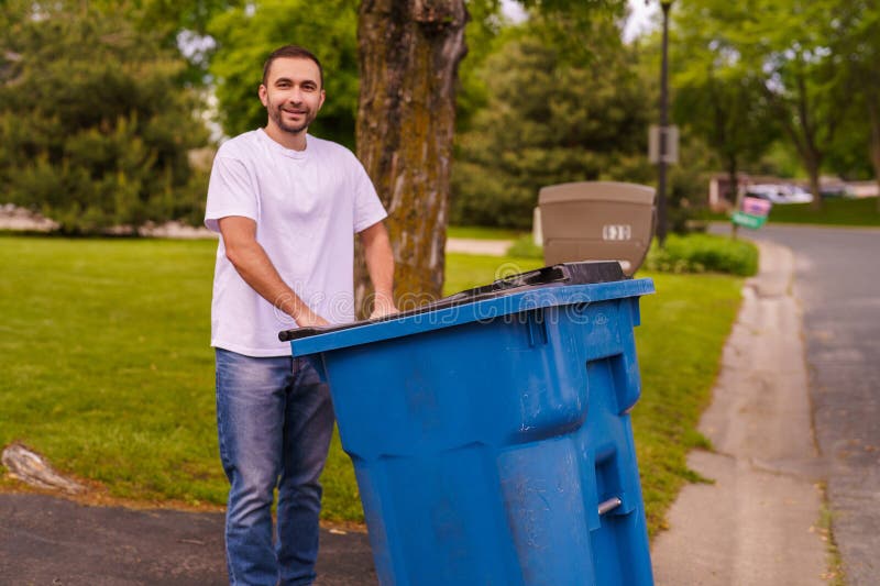 Young Man Pushes a Large Green Plastic Trash Bin for Weekly Waste ...