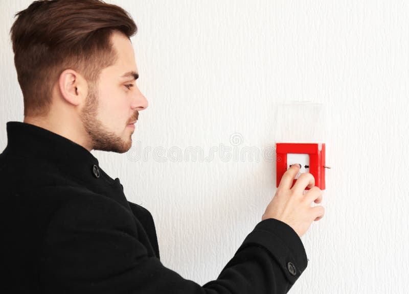 Young Man Pushing Button of Fire Alarm System, Indoors Stock Image ...