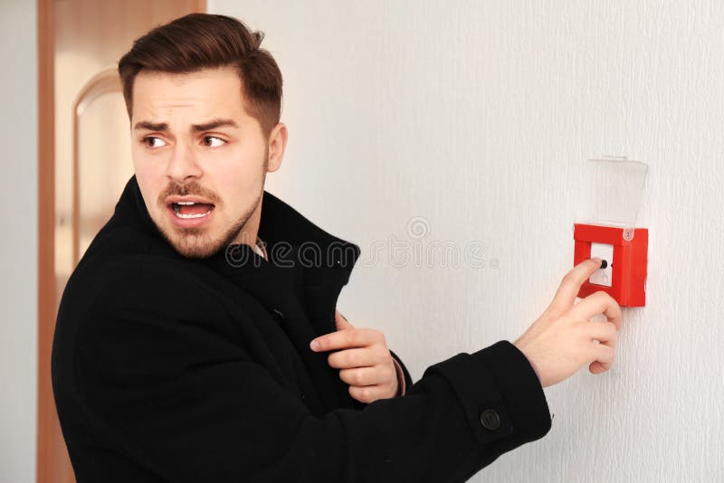 Young Man Pushing Button of Fire Alarm System, Indoors Stock Photo ...