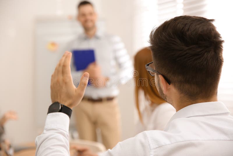 Young Man Raising Hand To Ask Question at Business Training in Room ...