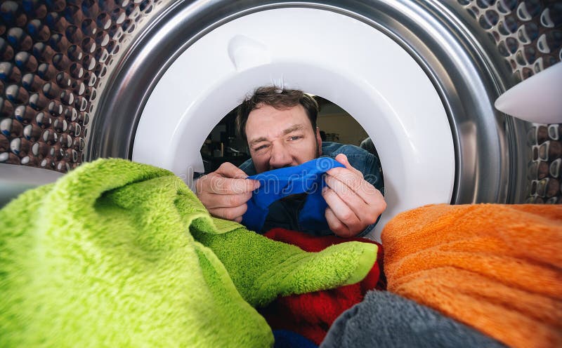 Young Man Reaching Inside a Washing Machine or Dryer Doing Laundry View ...