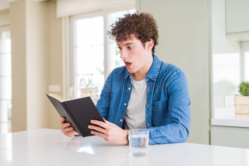 Young Man Reading a Book at Home Scared in Shock with a Surprise Face ...