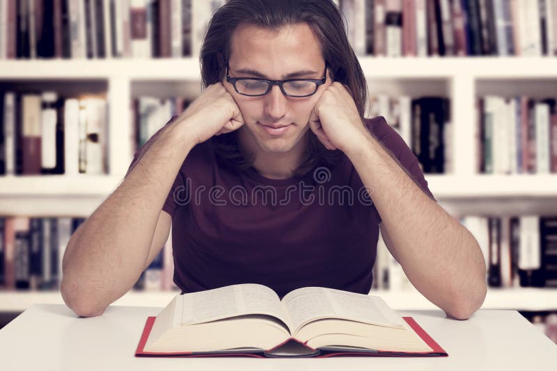 Young Man Reading Book in Library Stock Image - Image of young, library ...
