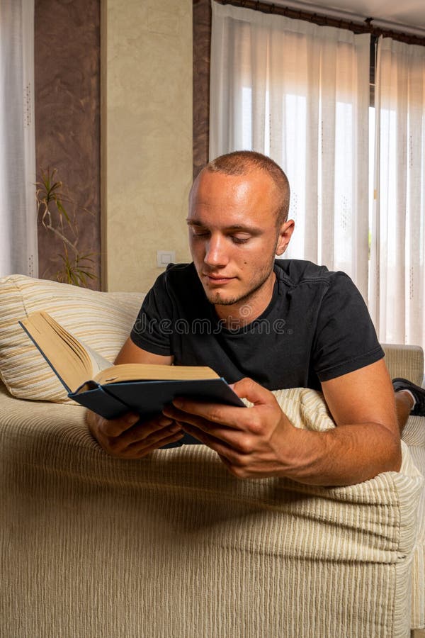 Young Man Reading a Book Lying Relaxed on the Sofa at Home Stock Image ...