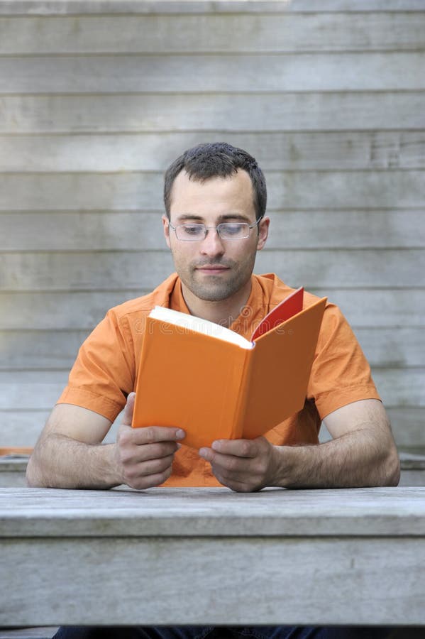 Young Man Reading a Book Outdoors Stock Photo - Image of outdoors, time ...