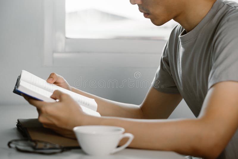 Young Man Reading Book at Work Desk in Free Time from Working at Home ...