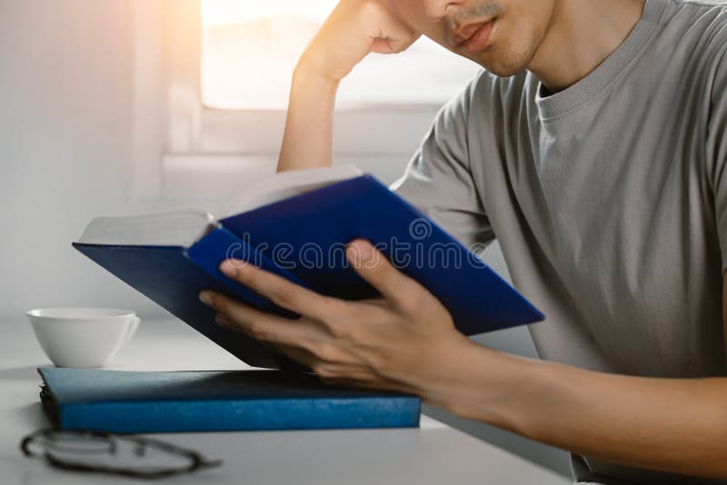 Young Man Reading Book at Work Desk in Free Time from Working at Home ...