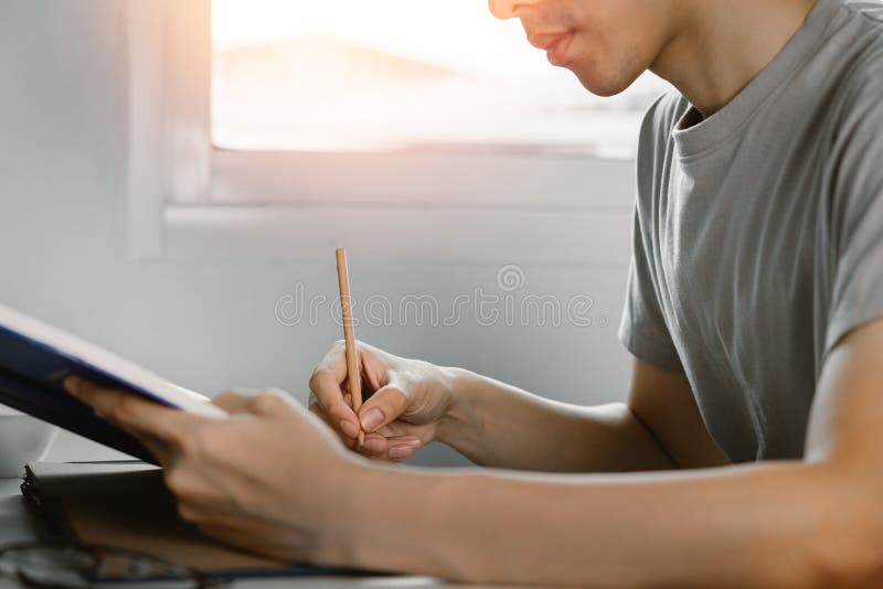 Young Man Reading Book and Writing in Note at Work Desk in Free Time ...