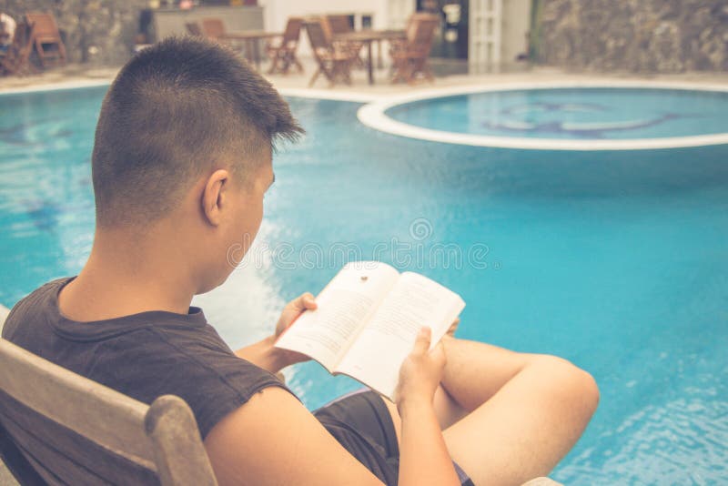 Young Man Reading Books beside the Pool Stock Image - Image of reading ...