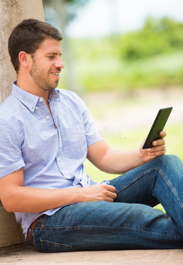 Young Man Reading E-book Outside Stock Image - Image of looking, field ...