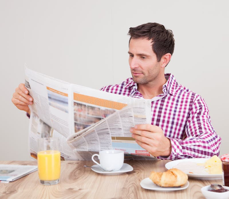 Young Man Reading Newspaper at Breakfast Stock Photo - Image of ...