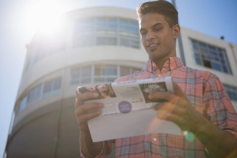 Young Man Reading Paper while Standing by Building Stock Image - Image ...