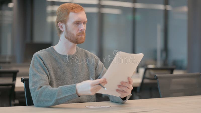Young Man Reading Reports while Sitting in Office Stock Image - Image ...