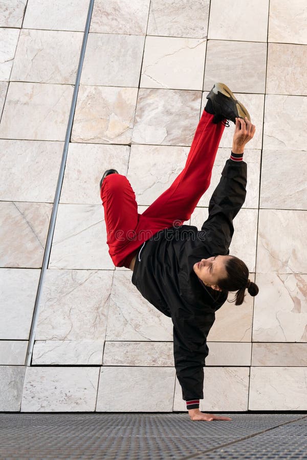 A Young Man in Red Pants Performs a Breakdance Pose on a Metal Grate ...